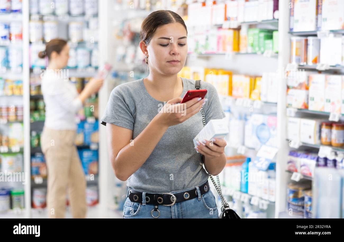 Using smartphone to read information - woman scans a QR code on package ...