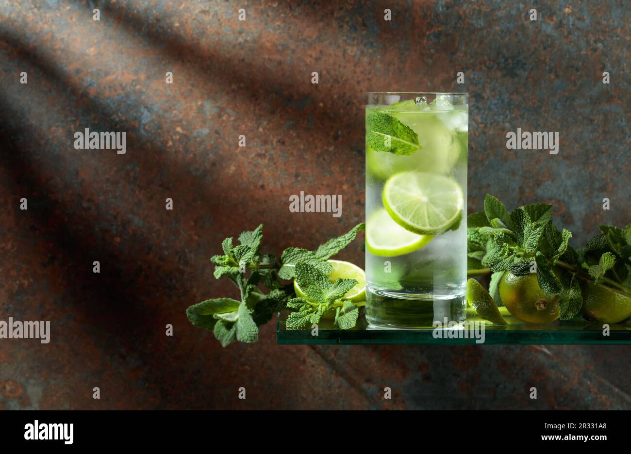 Mojito with ice, lime, and mint. Iced drink in a misted glass on a ...