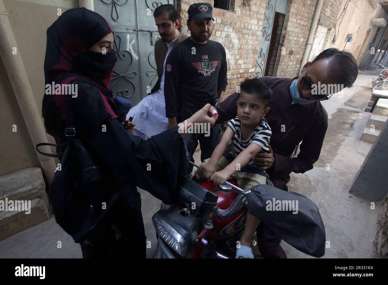 A health worker administers a polio vaccine to a child at a neighborhood of Peshawar, Pakistan ...