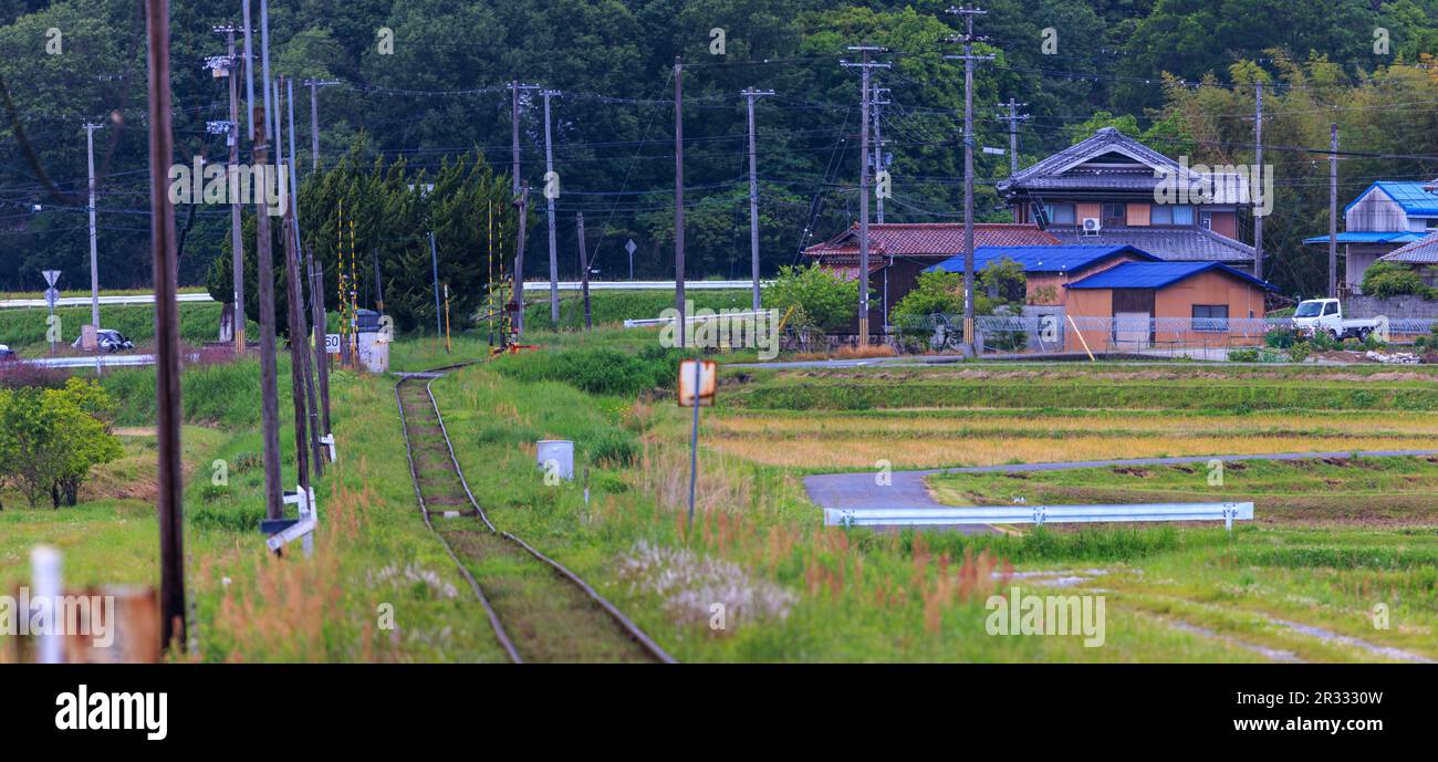 Train tracks and electrical wires by large house in rural Japan ...