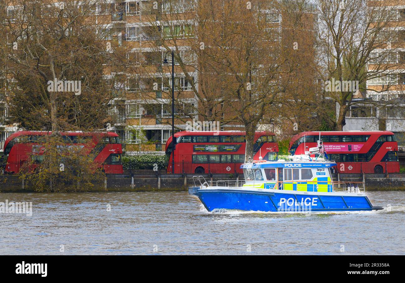 A Metropolitan police boat on the river Thames passes three double ...