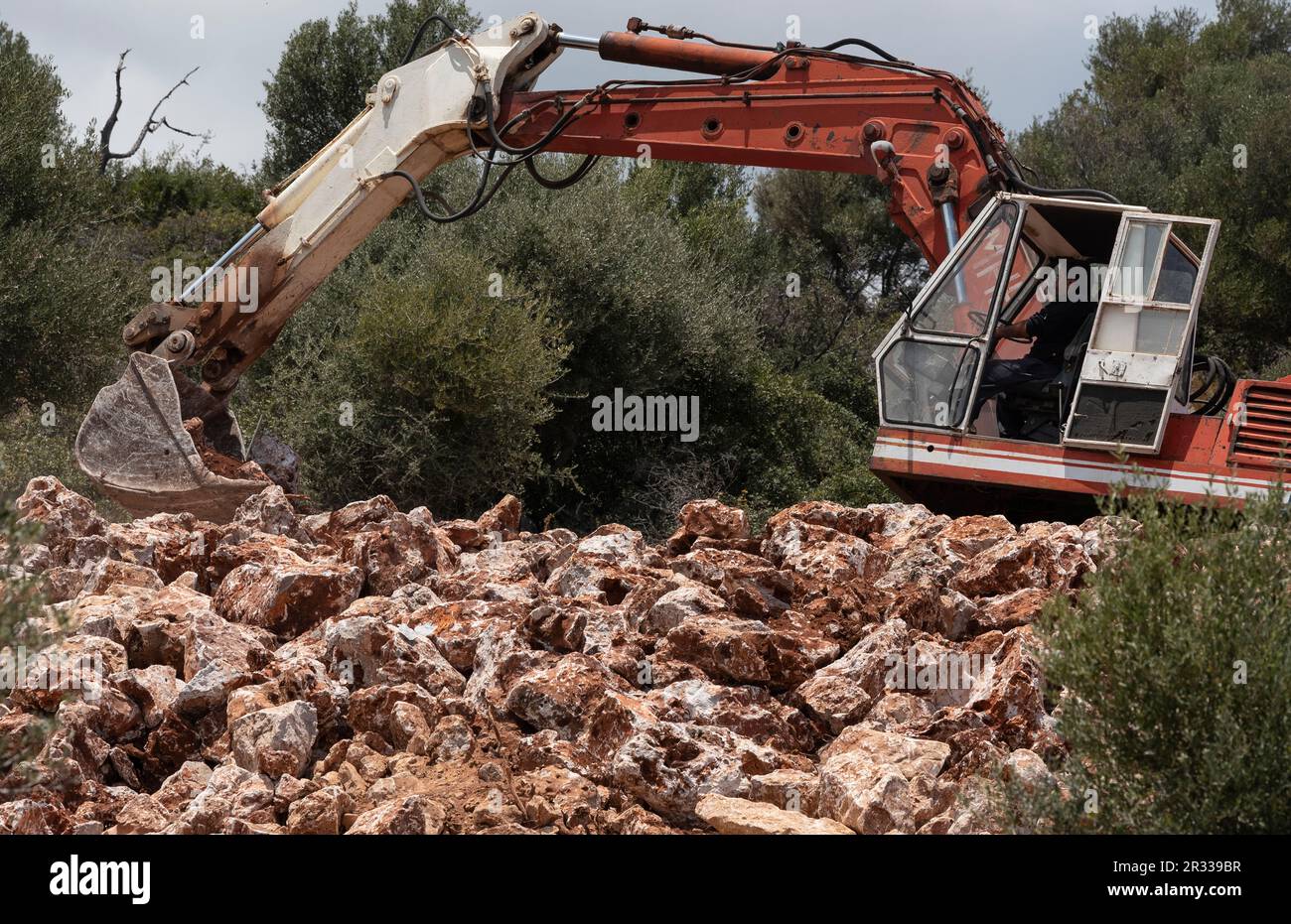 Crete, Greece, Europe. 2023. Excavator machine moving rocks into a ...