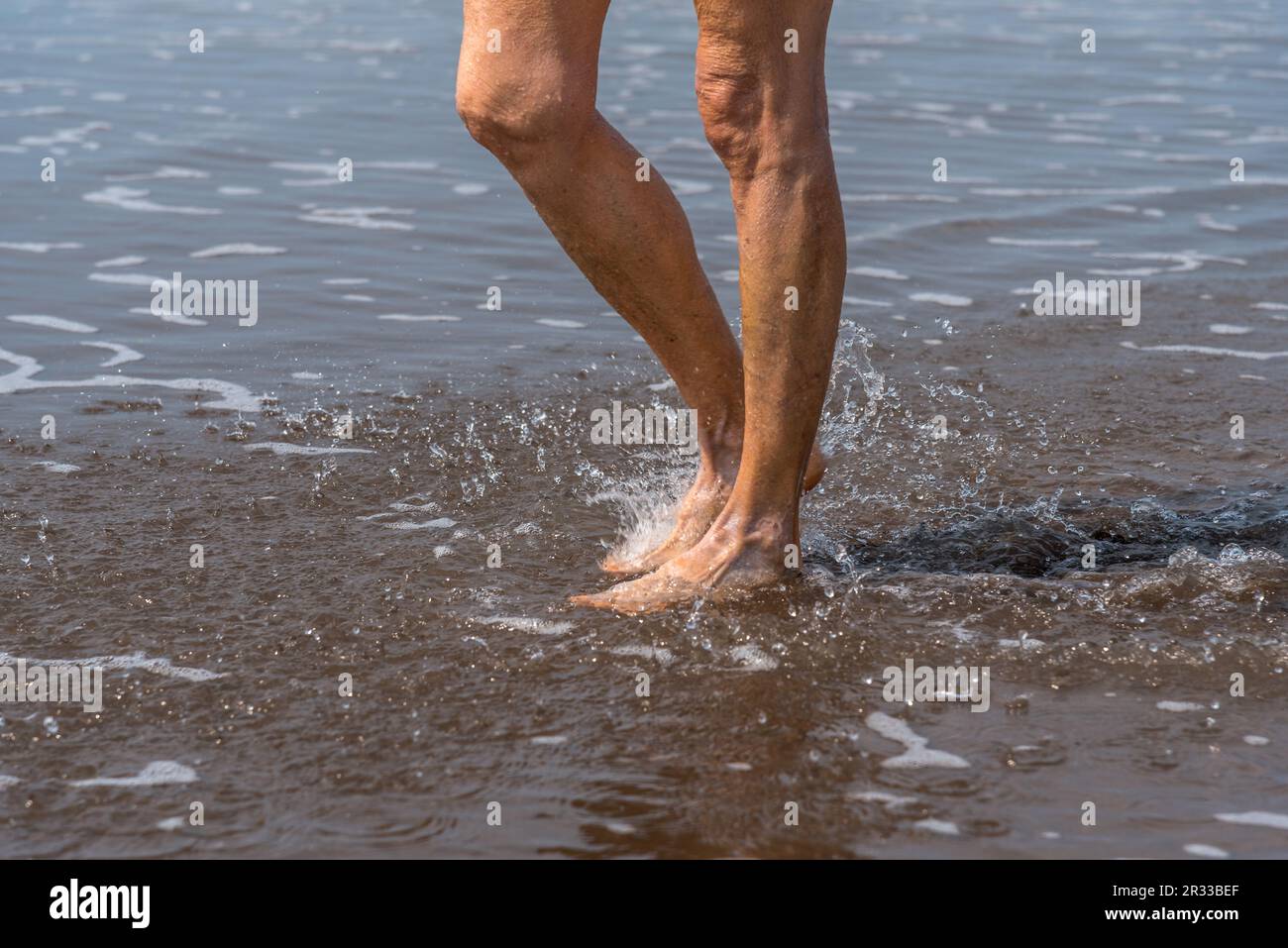 Barefoot person walking along the seashore on the beach Stock Photo - Alamy