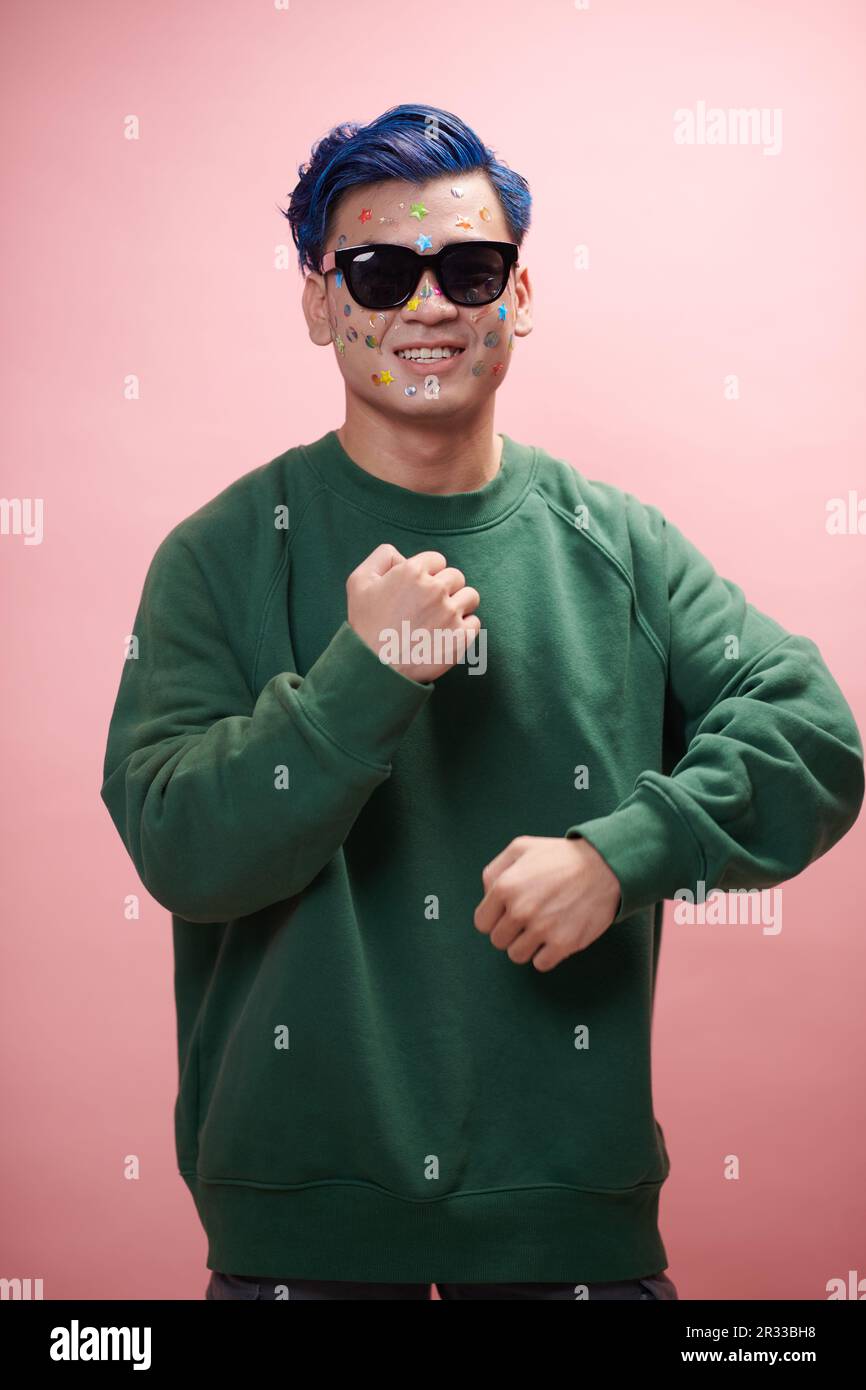Joyful young man with stickers on face and sunglasses dancing Stock ...