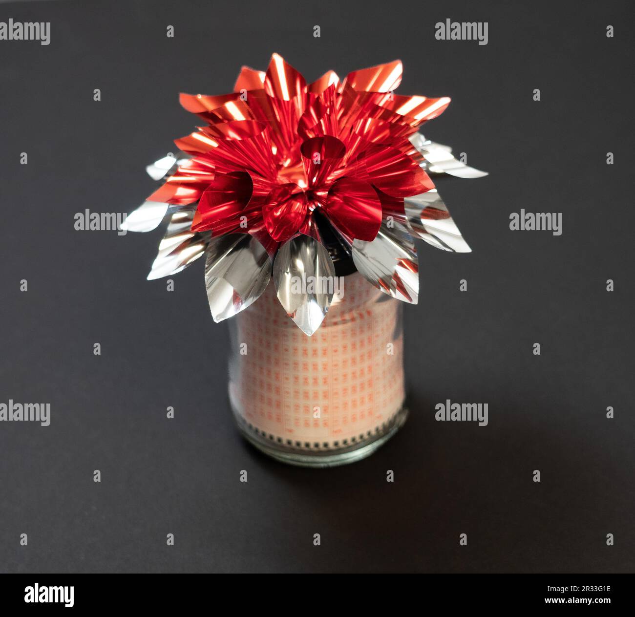 Lottery ticket as a gift in a jar with red silver bow, isolated on ...