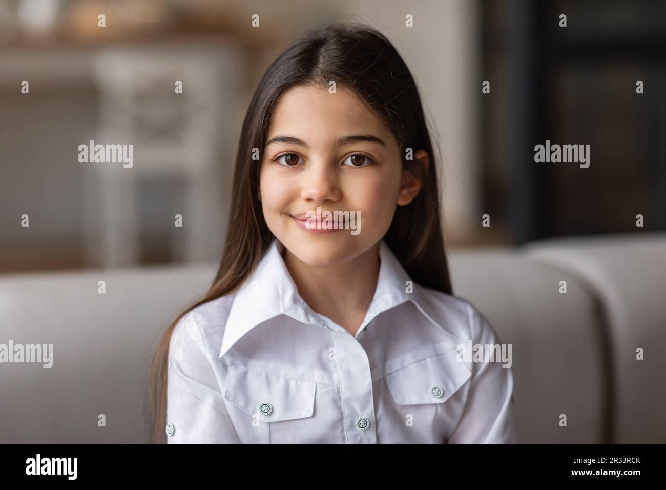 Headshot Of Cheerful Preteen Schoolgirl Posing Sitting On Couch Indoors