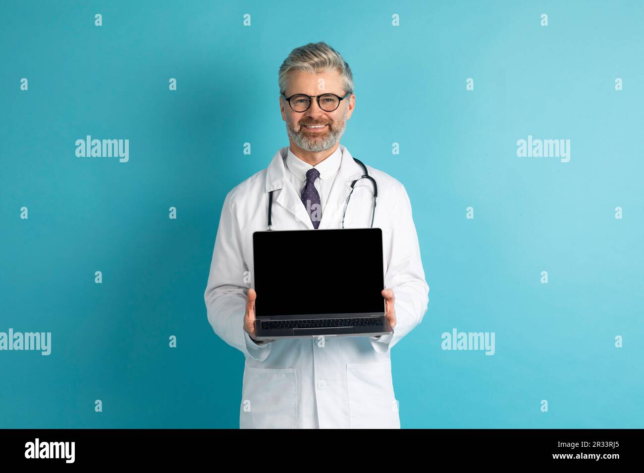 Positive middle aged doctor showing laptop with black screen Stock ...