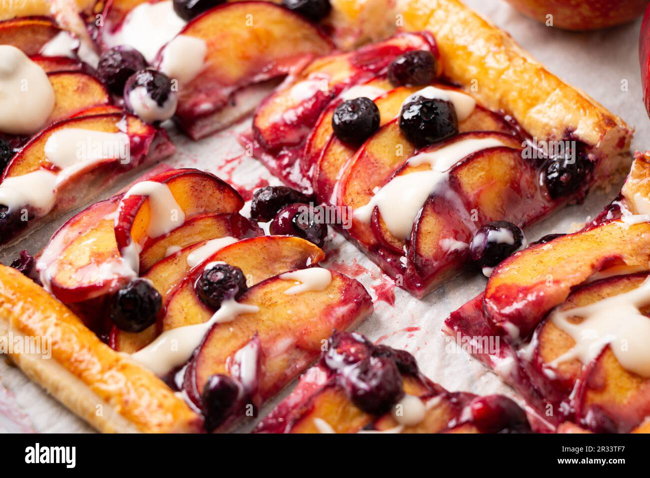 Nectarine and blueberry puff pastry pie with vanilla glaze cut into ...