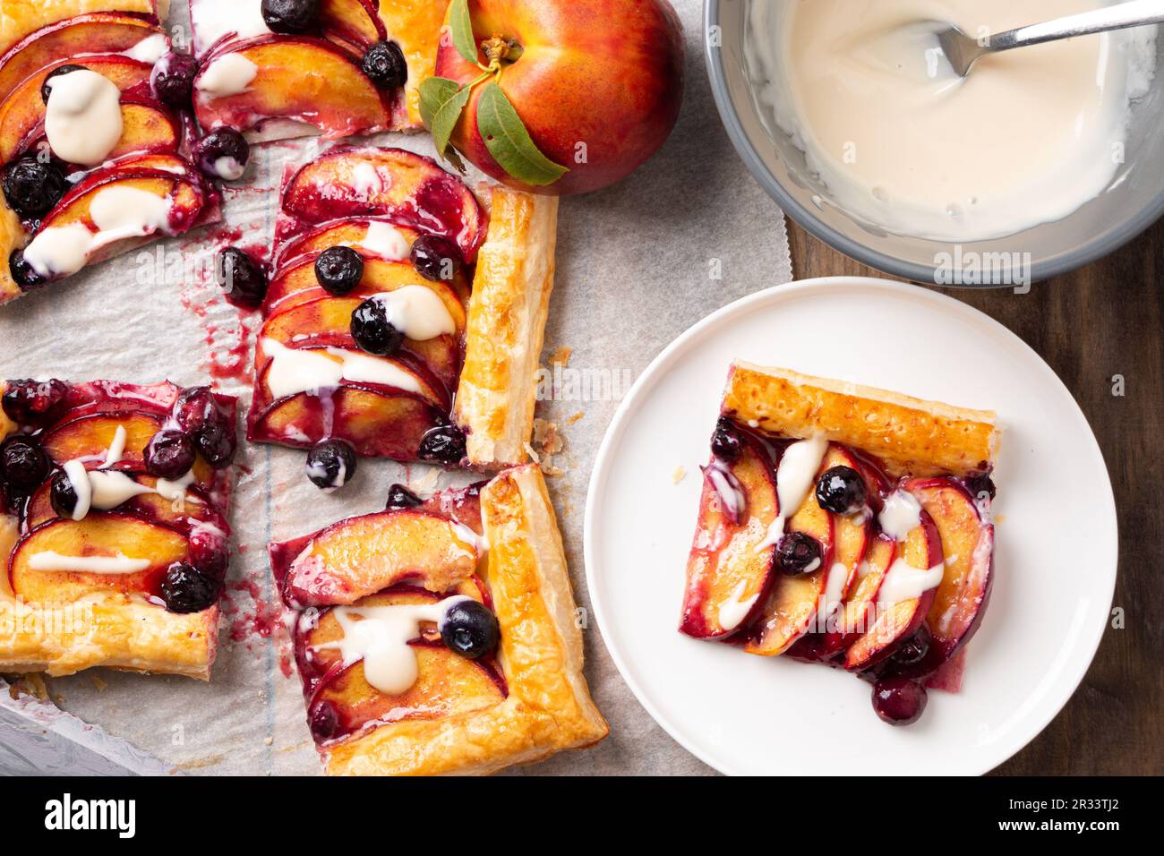 Nectarine and blueberry puff pastry pie with vanilla glaze cut into ...