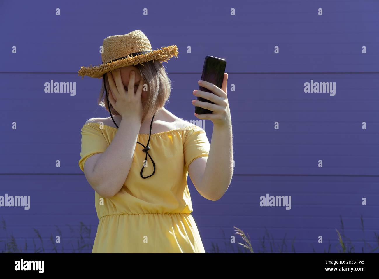 A beautiful Asian girl in a straw hat and a yellow dress covers her ...