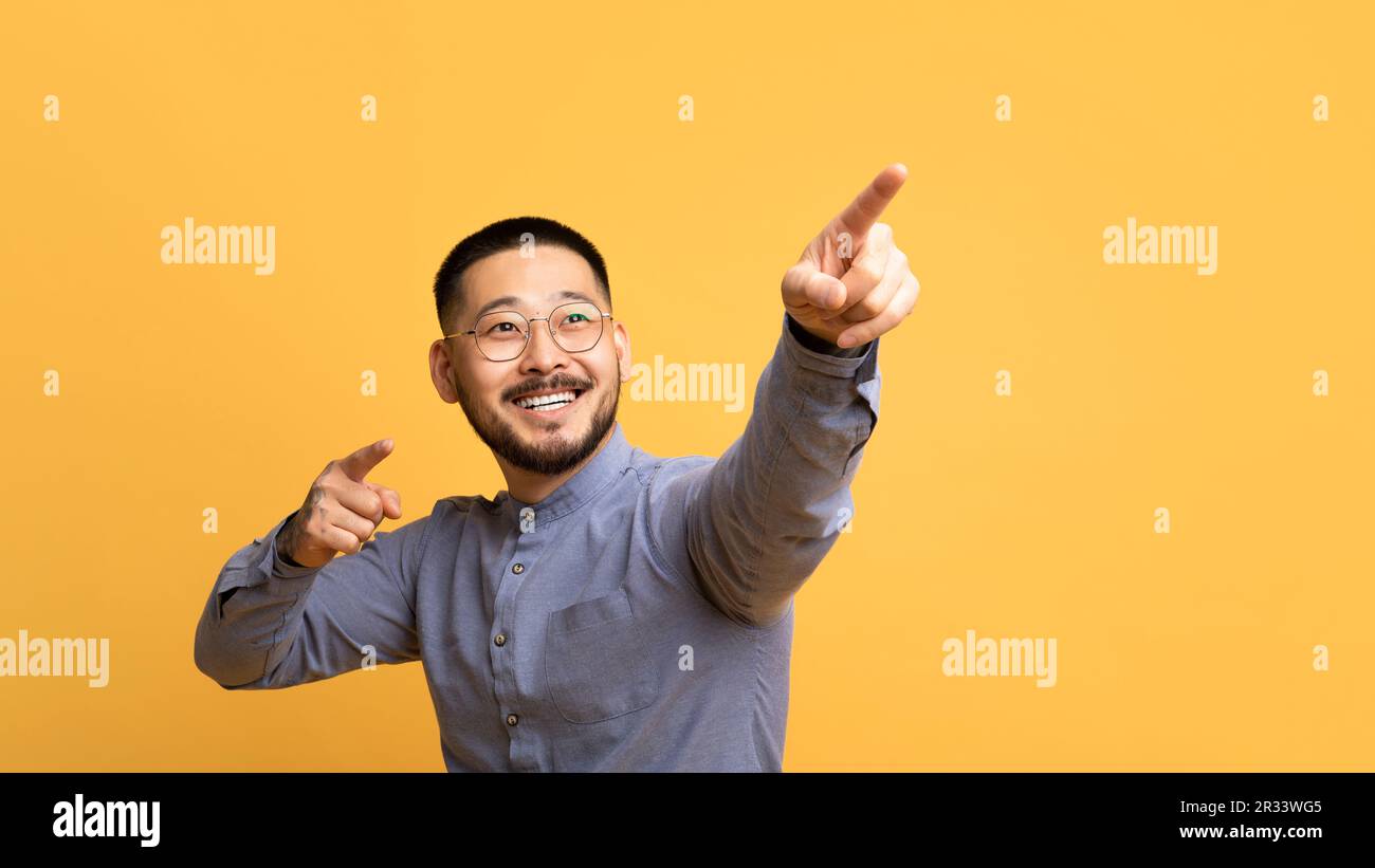 Gotcha. Cheerful asian man pointing away with two hands Stock Photo - Alamy