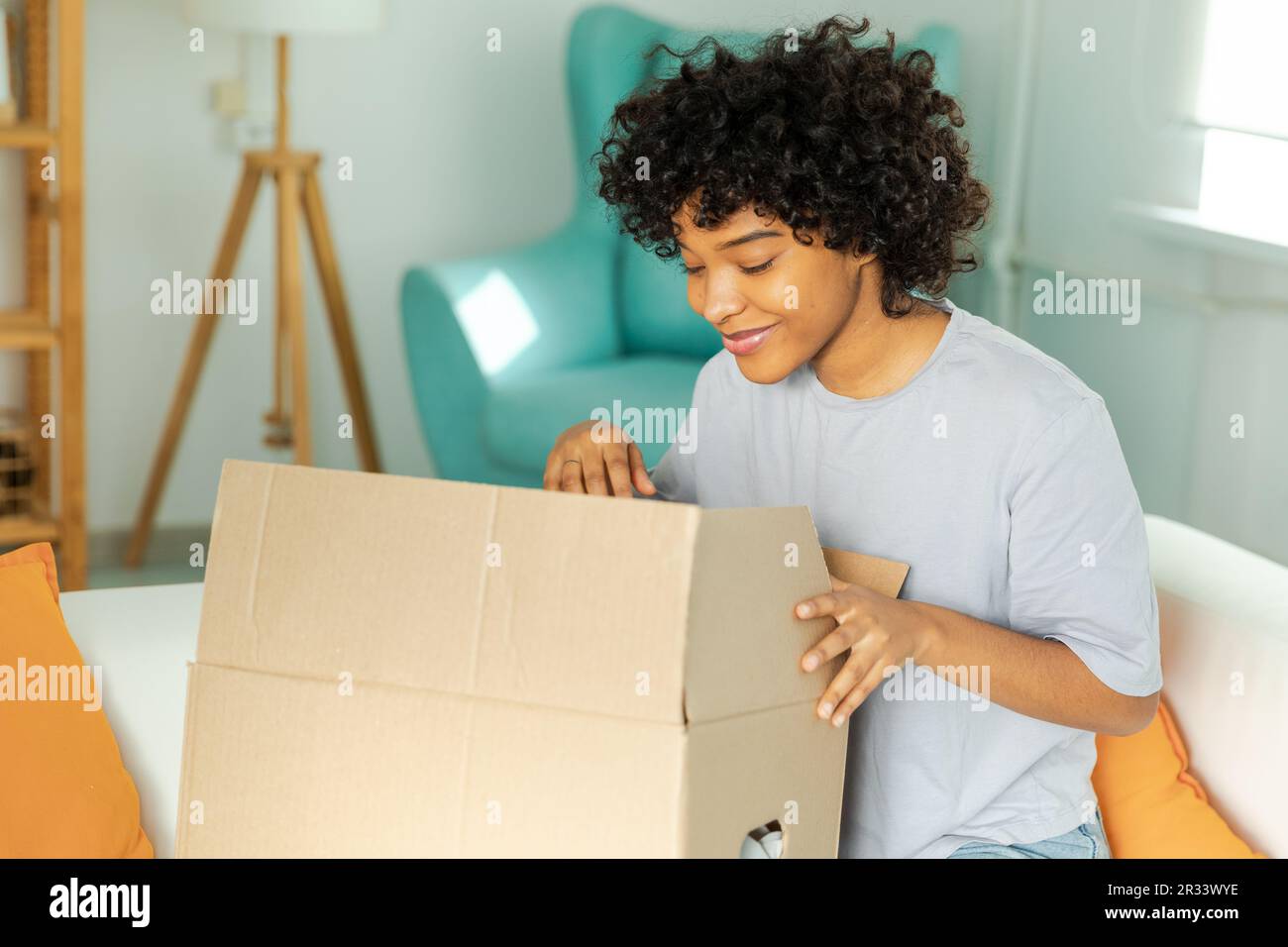 African girl unpacking delivery looking in box. Happy woman opening ...