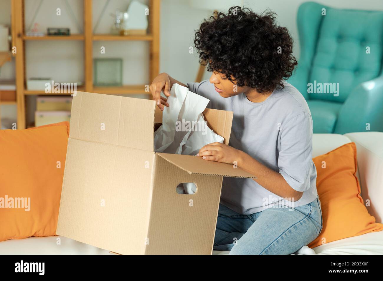 African girl unpacking delivery looking in box. Happy woman opening ...