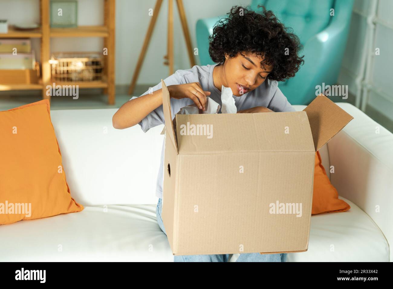 African girl unpacking delivery looking in box. Happy woman opening ...