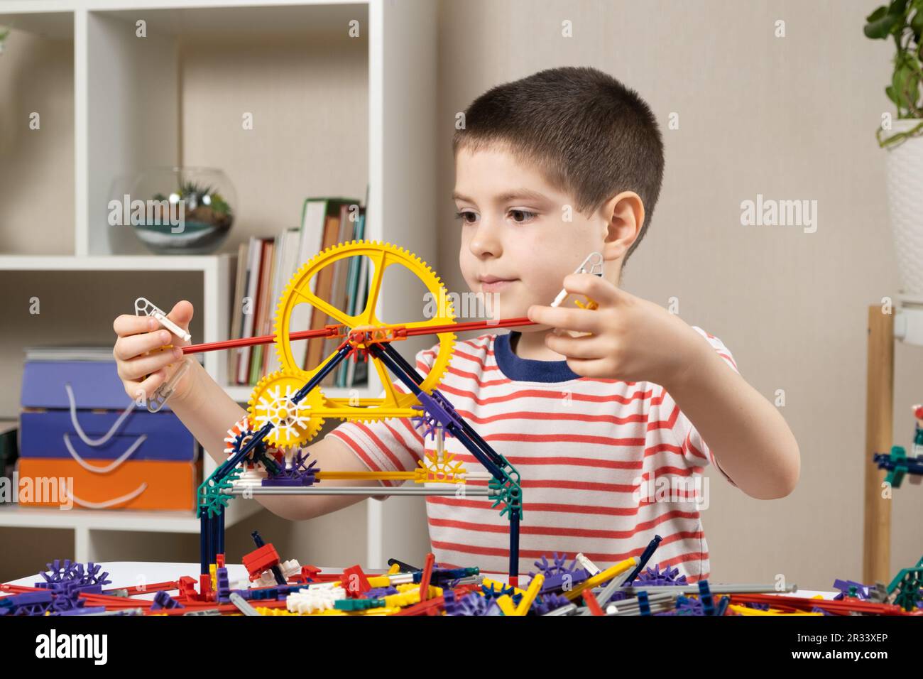 A little boy plays with a constructor, creating figures from gears and ...