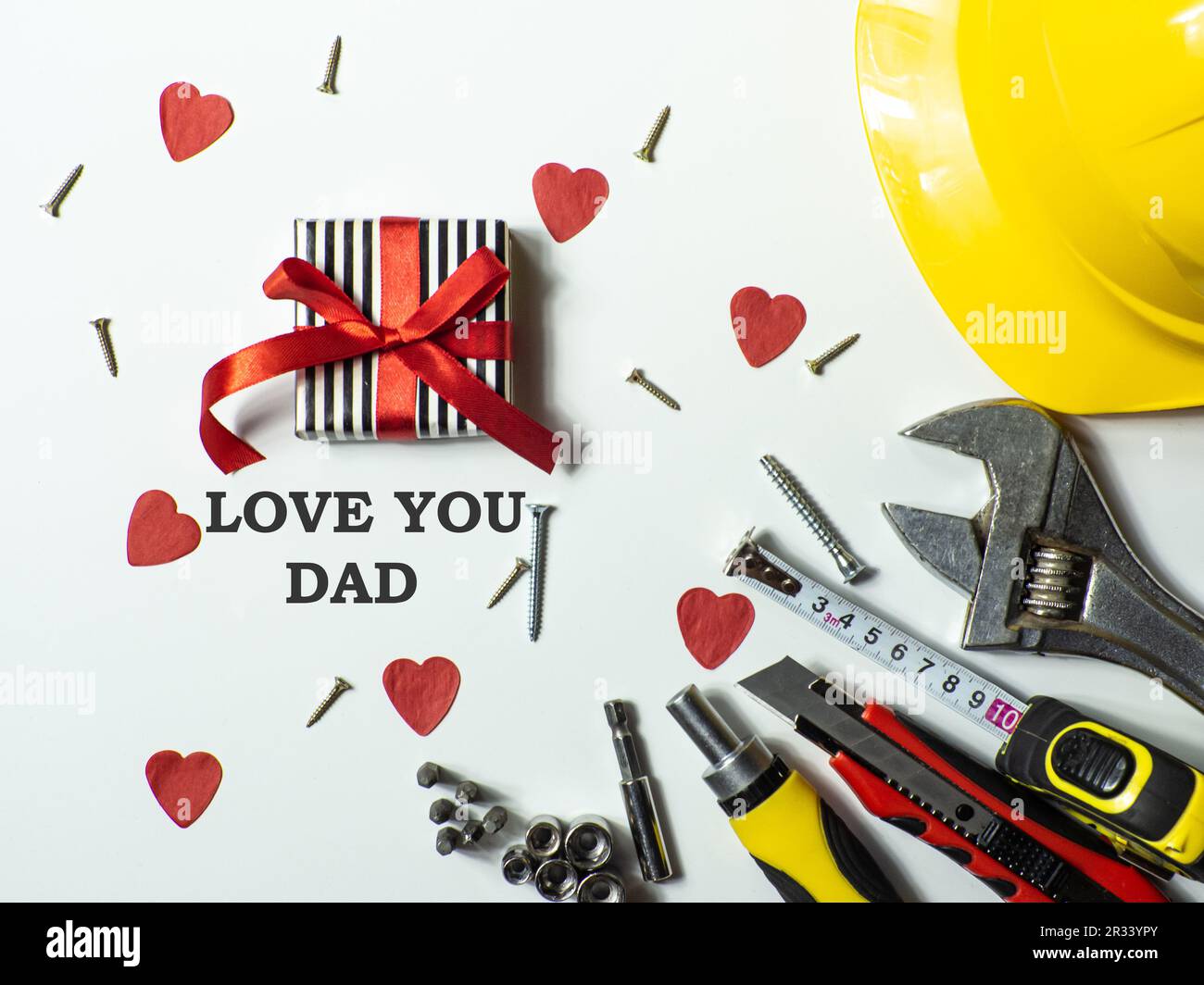 Construction tools, hard hat and wrapped gift box with a bow on white ...