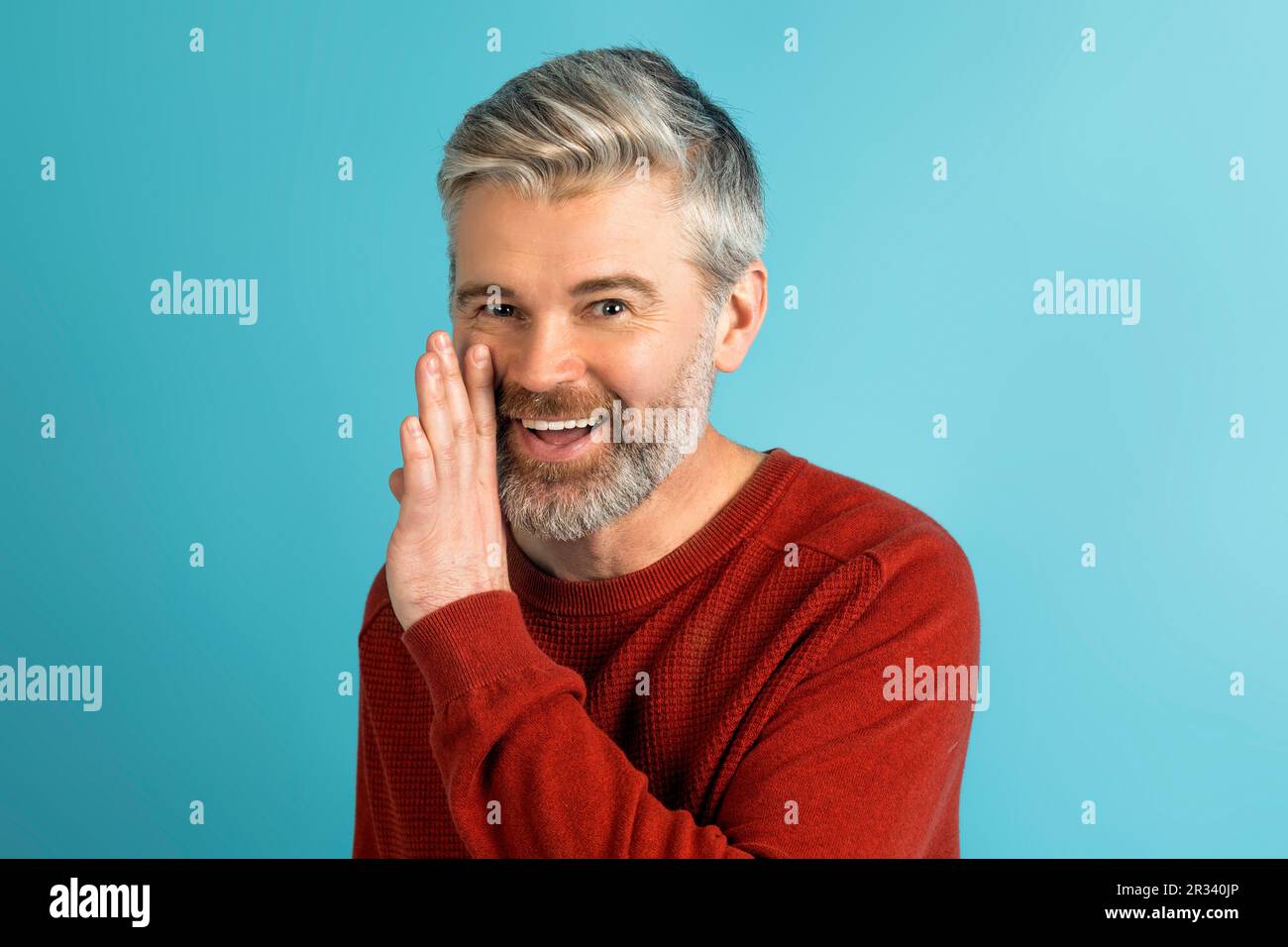 Happy middle aged man holding hand next to mouth Stock Photo - Alamy