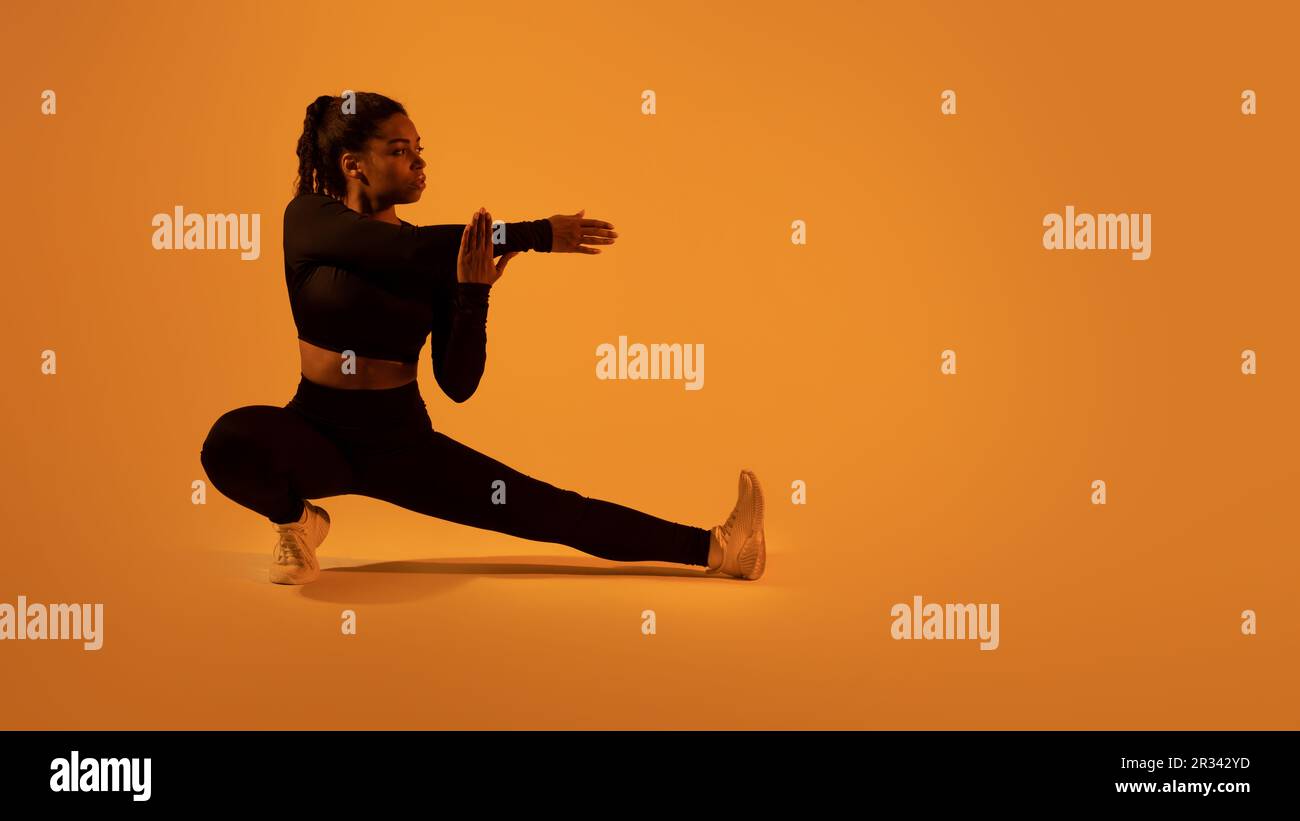 Exercising with precision. Black woman doing deep side squat exercise ...