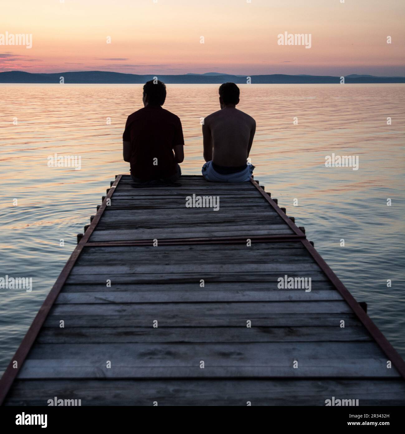 Friends sitting on beach sunset hi-res stock photography and images - Alamy