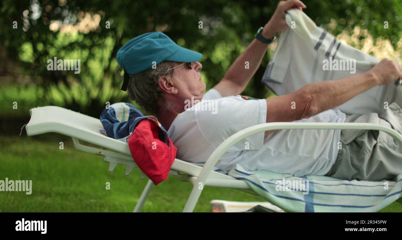 Retired man preparing to rest, lying down and covering body with towel ...