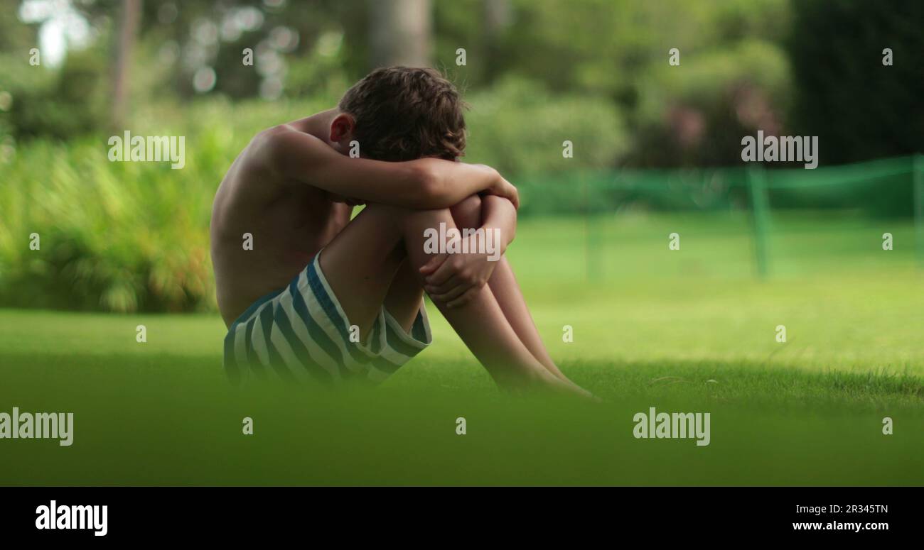 Sad upset child boy with head down in outdoor park Stock Photo - Alamy