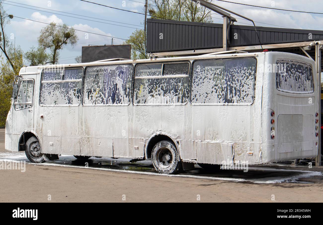 Big white bus in foam at a self-service car wash. External washing of ...