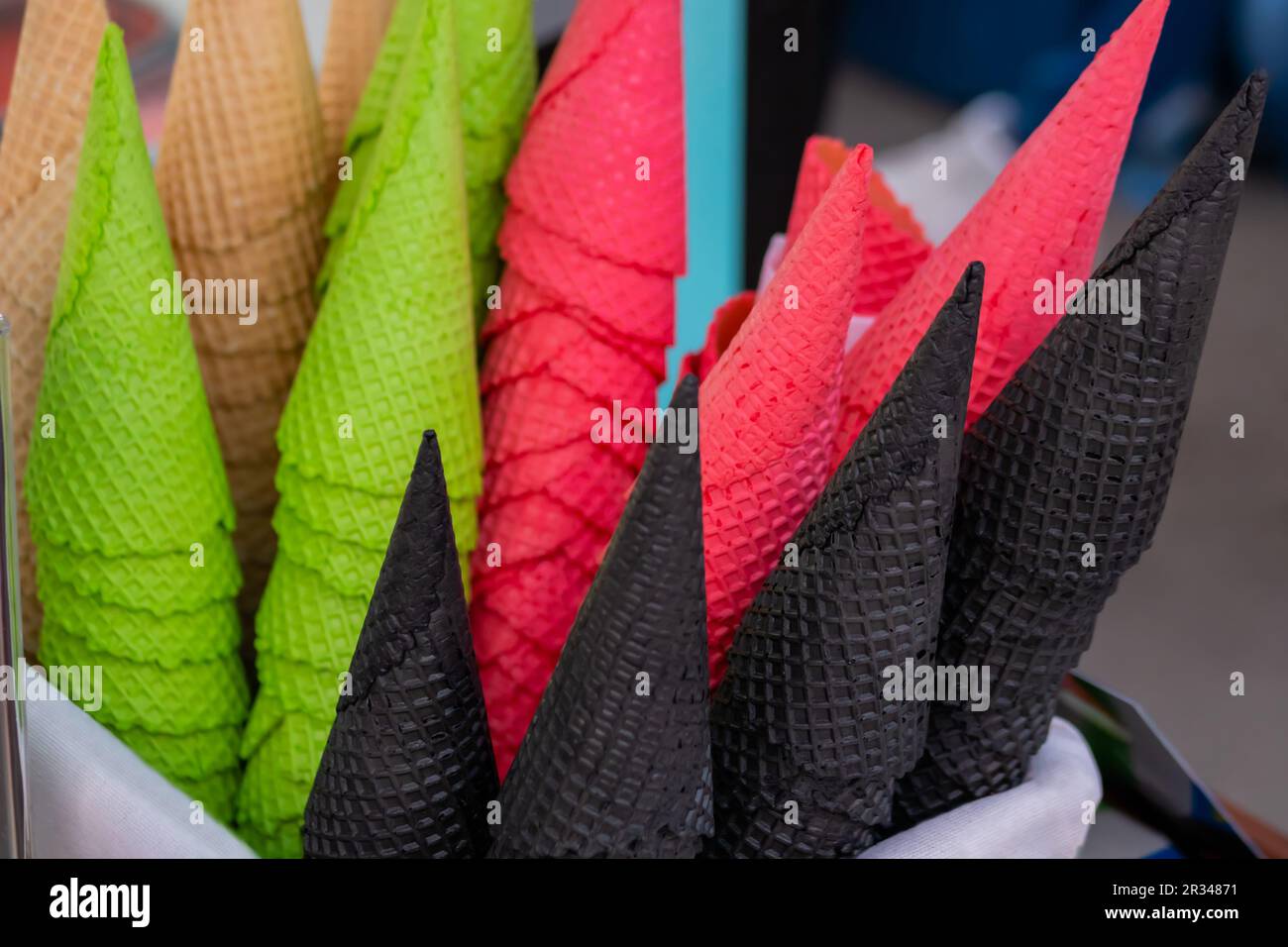Stacks of many colorful empty waffle cones at outdoor food market ...