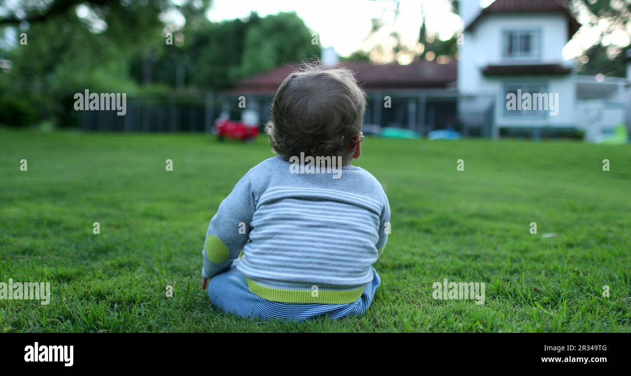 Toddler baby hanging outside in home grass backyard garden, residential ...