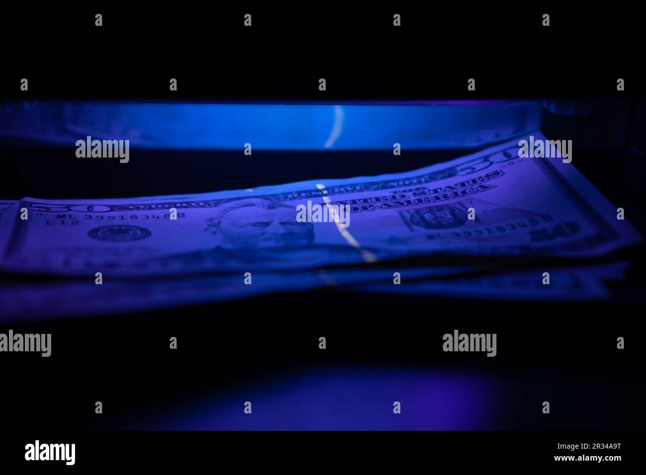 Close-up of dollars under an ultraviolet lamp. Inspection of a dollar ...