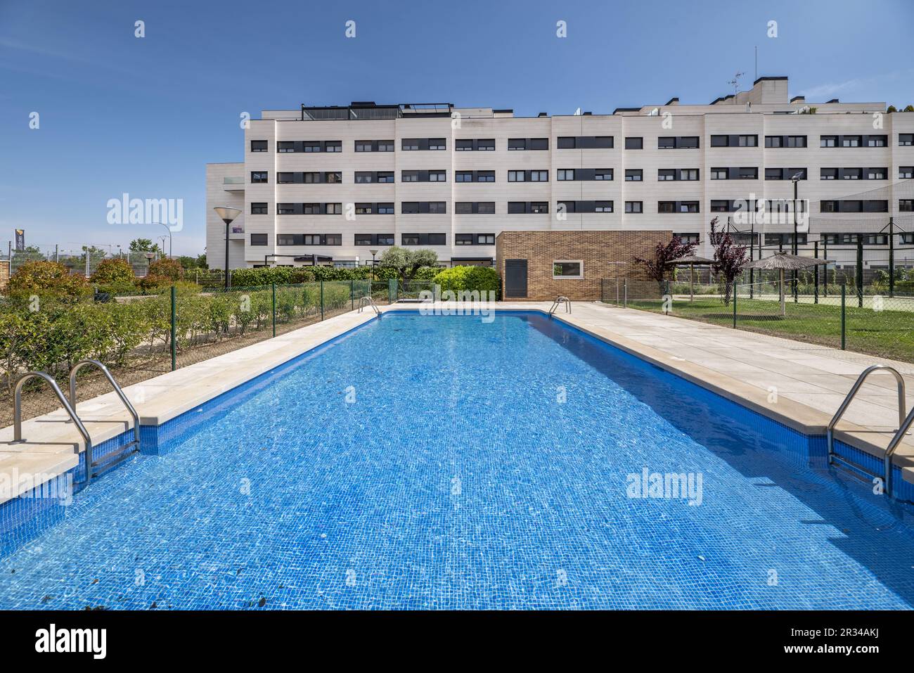 Pool of an urban development with blue stoneware-type coating, gardens ...