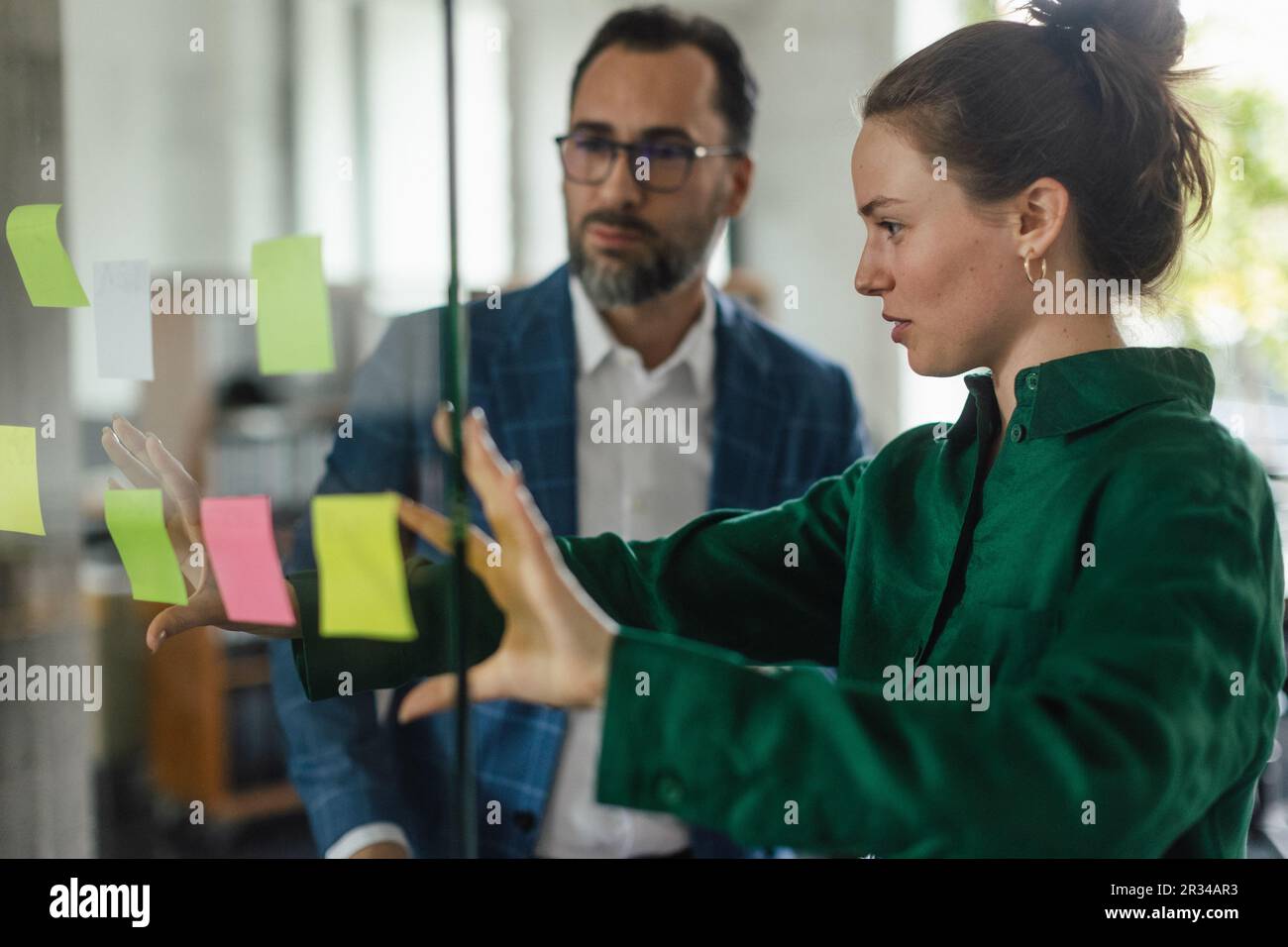 Young woman showing notes in office to her colleague Stock Photo - Alamy