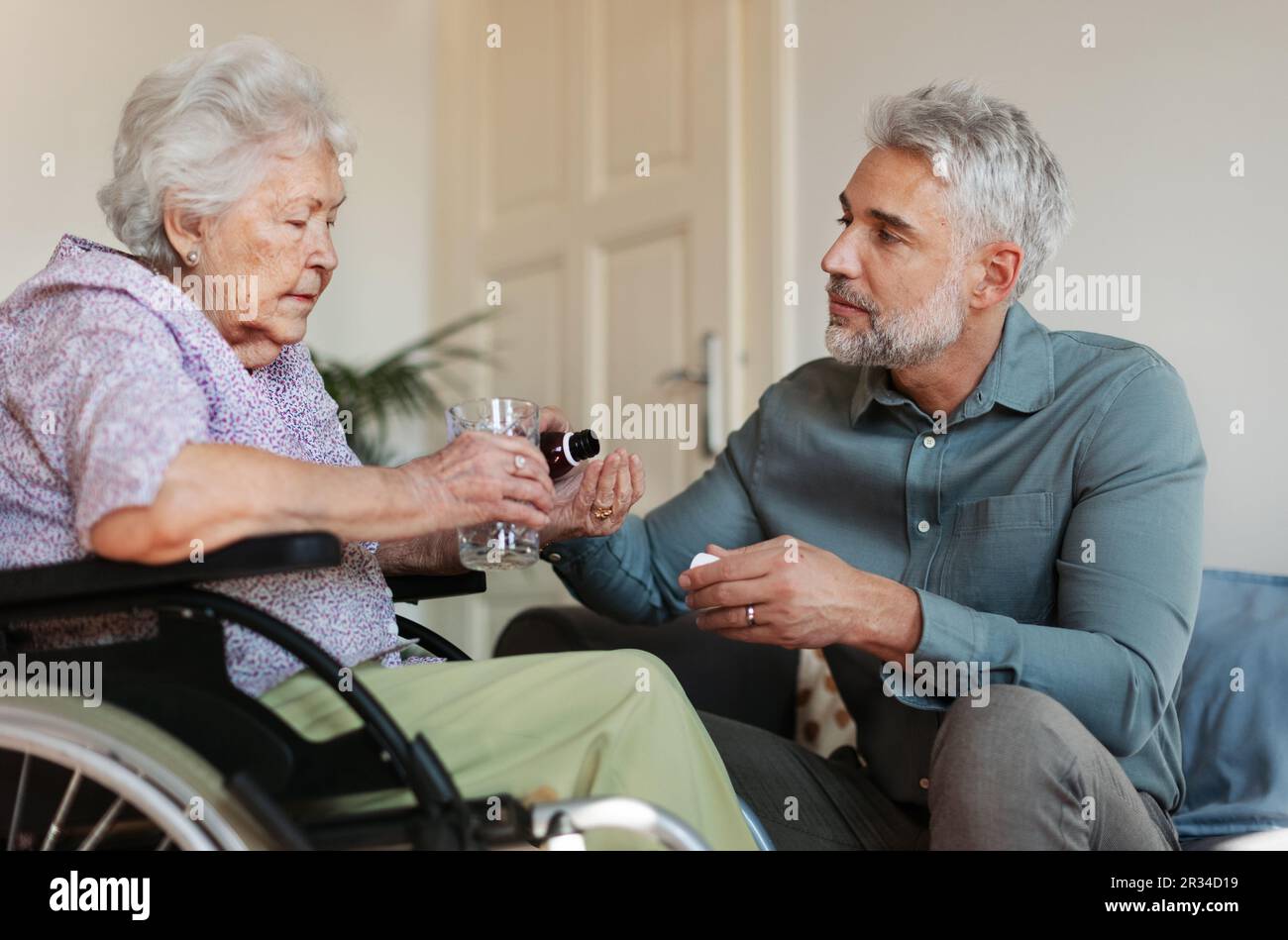 Adult son giving pills to his ill mother, helping to take medication ...