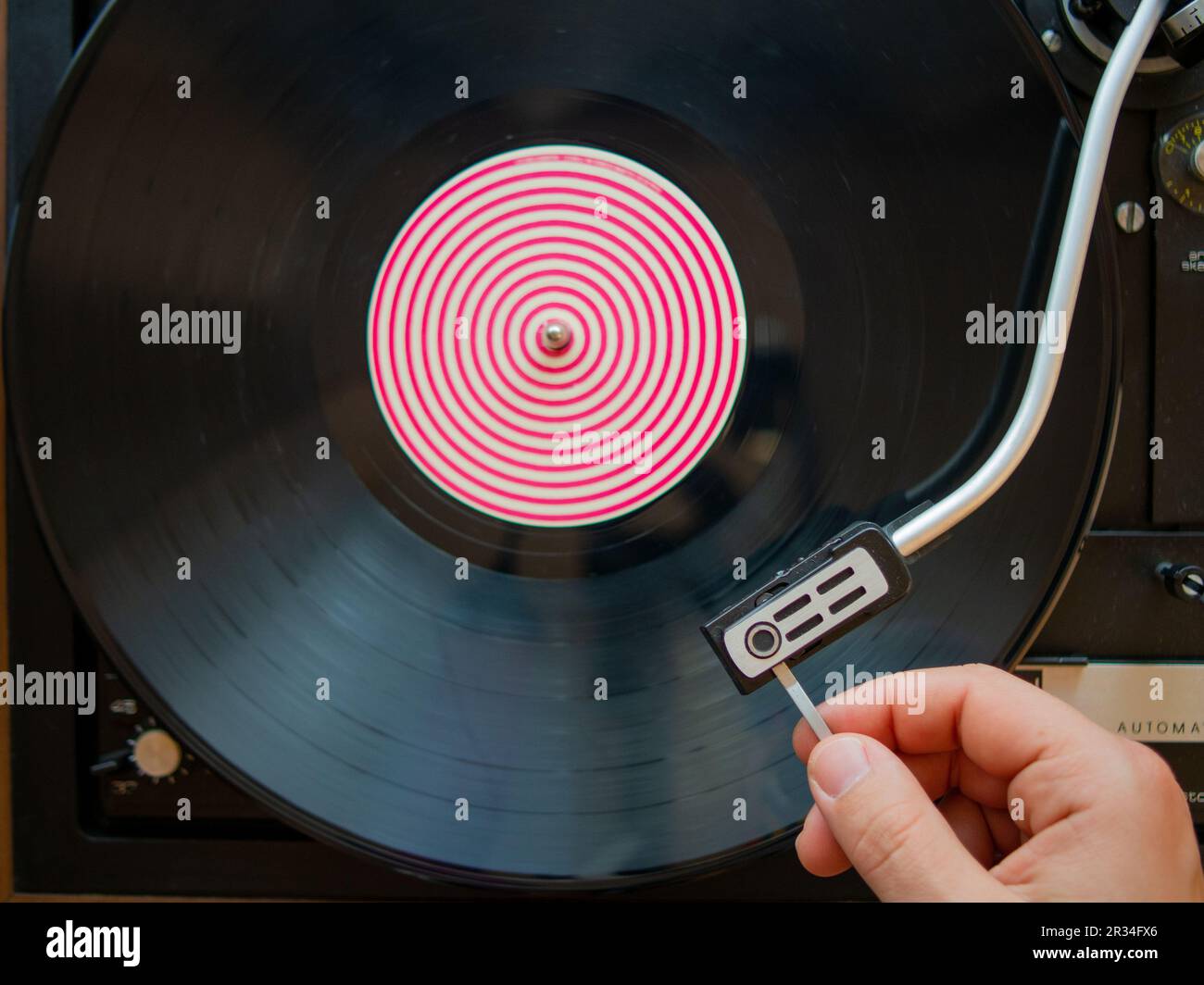 Detail of a male hand placing the needle on the track of a black vinyl ...
