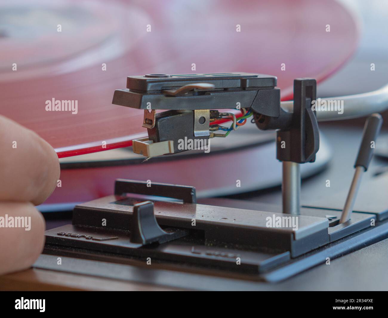Detail of a male hand placing the needle on the track of a red vinyl ...