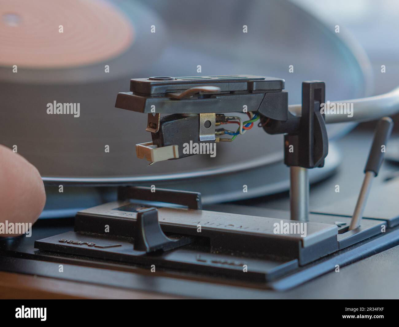 Detail of a male hand placing the needle on the track of a black vinyl ...