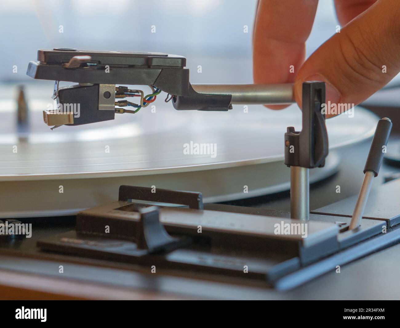 Detail of a male hand placing the needle on the track of a white vinyl ...
