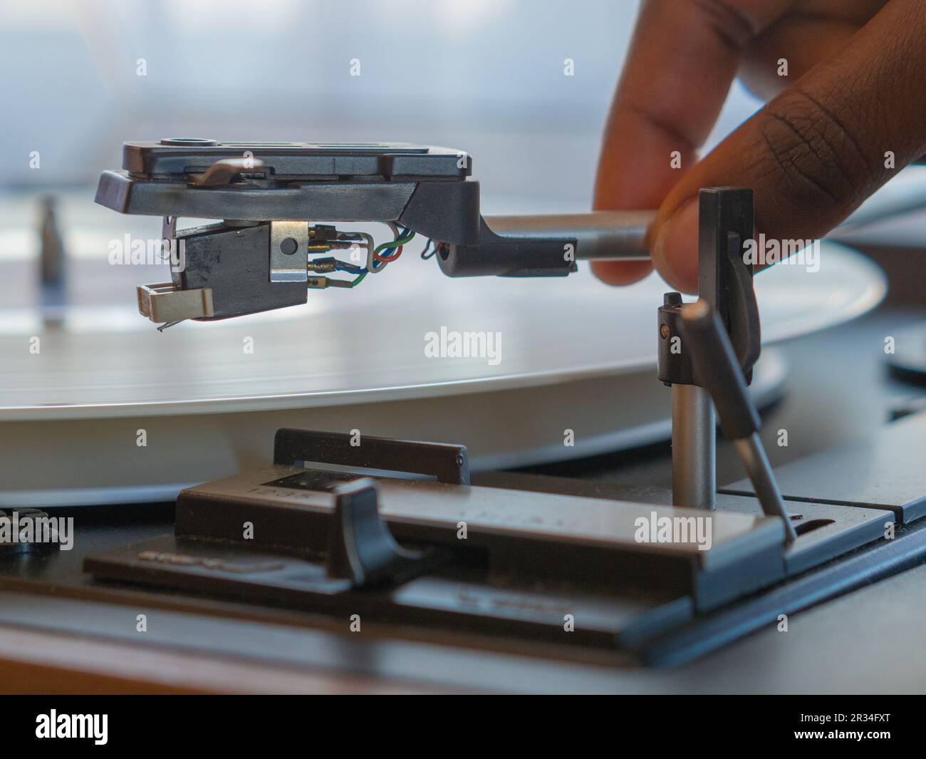 Detail of a female hand placing the needle on the track of a white ...