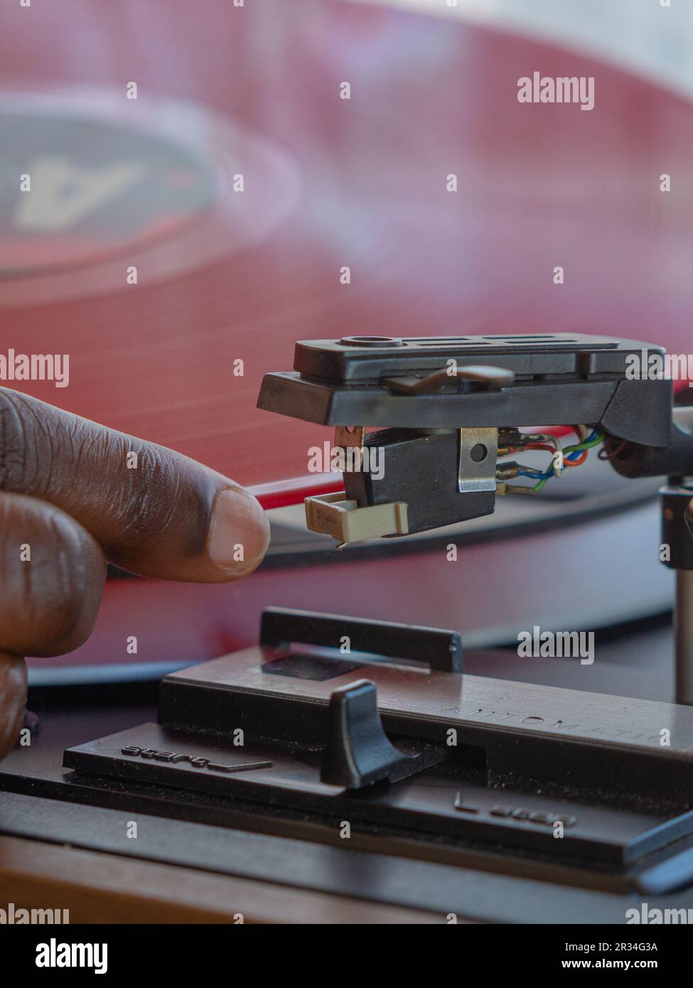 Detail of a female hand placing a red vinyl record on a vintage ...