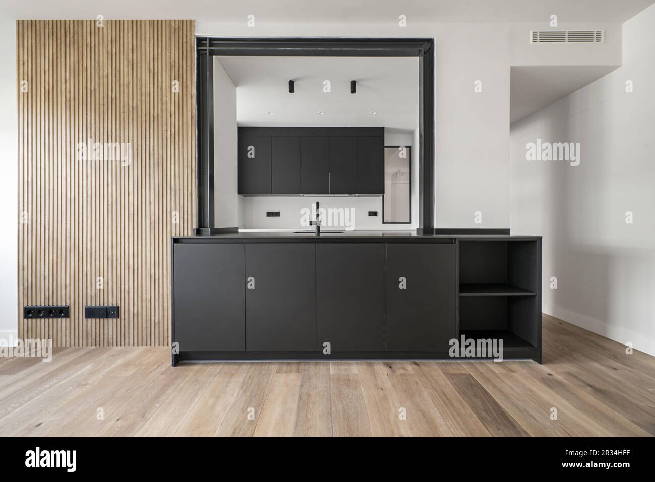 Living room of a house with black furniture, a wooden mural and a wide ...