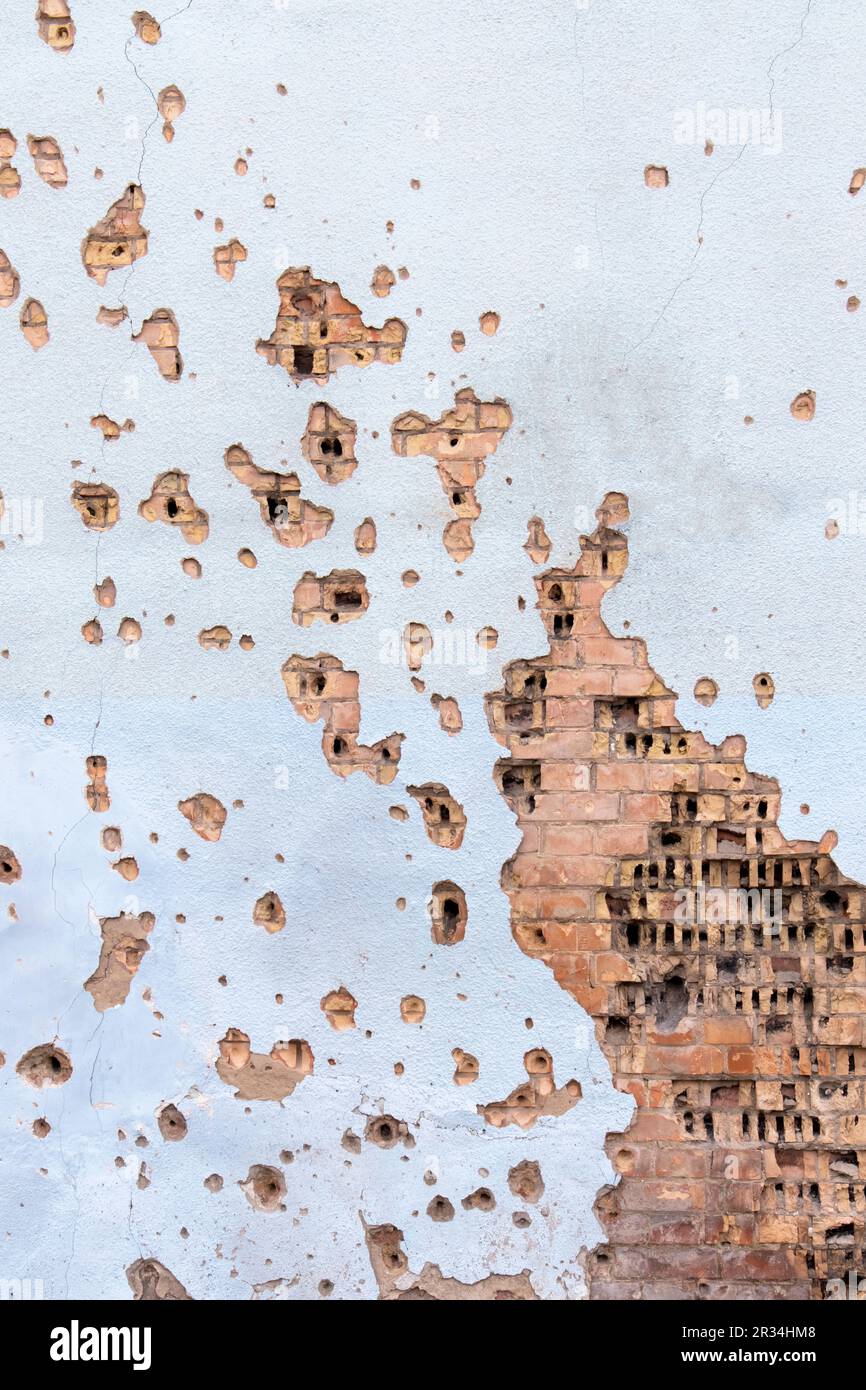 The wall of a building battered by rocket fragments in a war zone ...