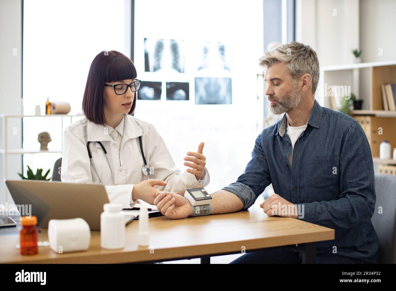 Attractive cardiologist telling patient about all possible reasons of ...