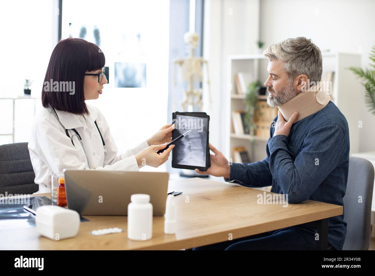 Female doctor with stethoscope and male patient in neck brace sitting ...