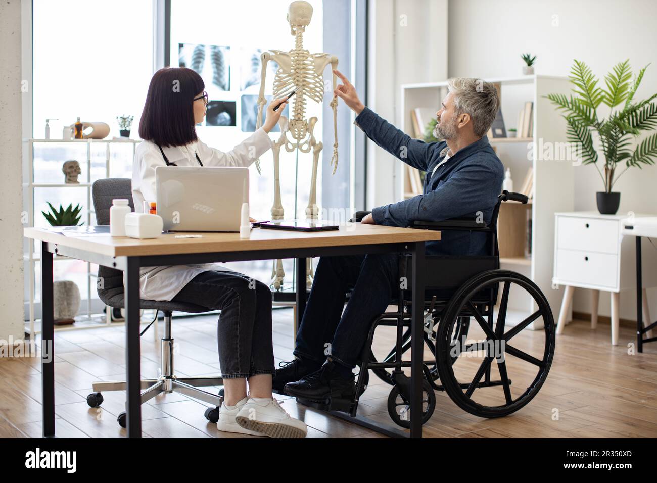 Full length view of female physician and man with disability examining ...