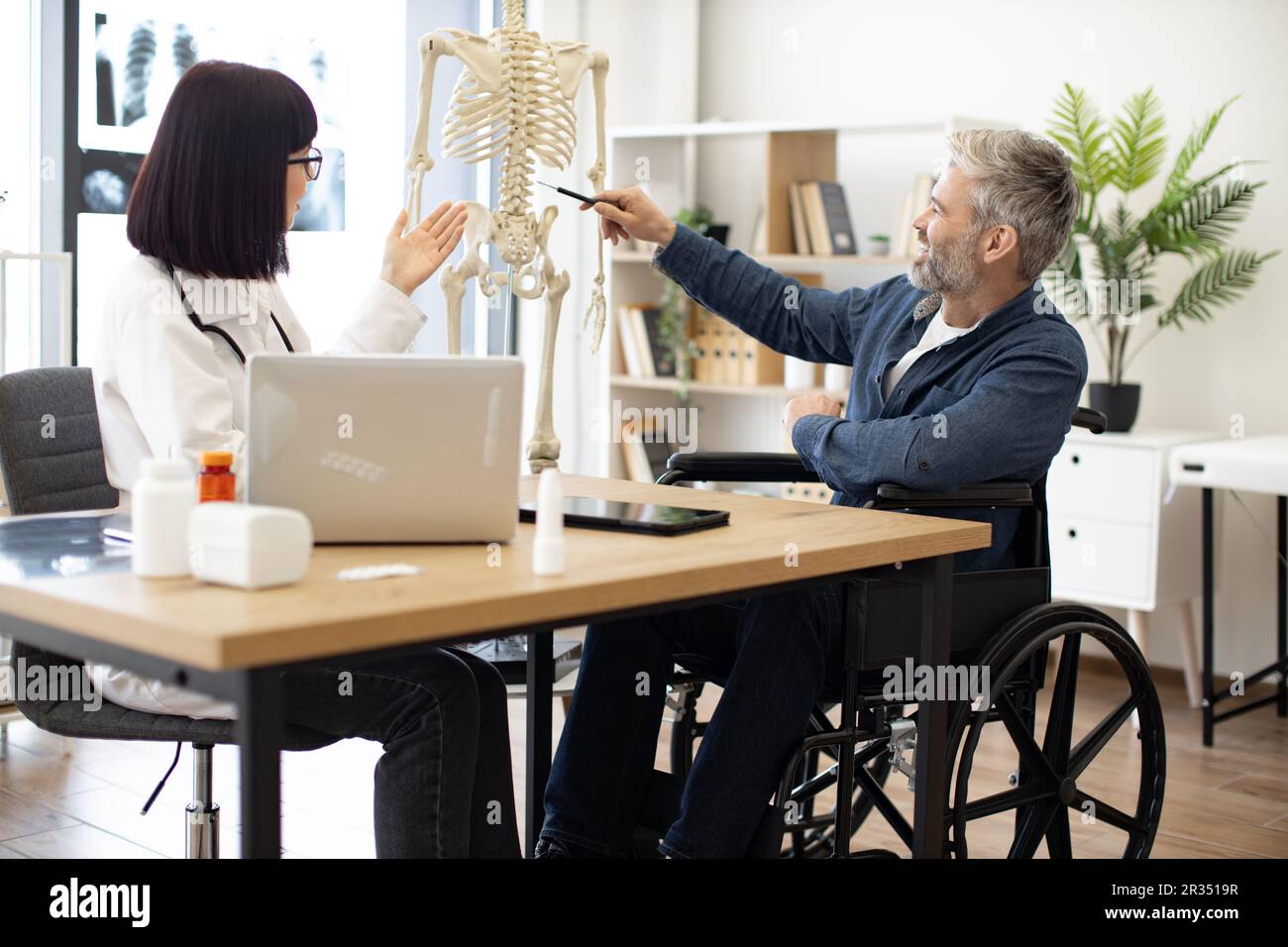 Full length view of female physician and man with disability examining ...