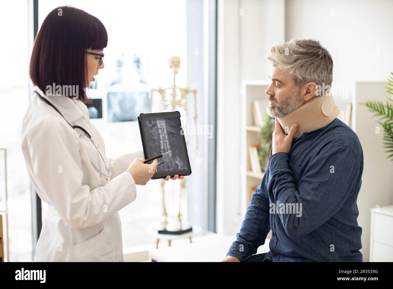 Caucasian lady holding tablet with CT scan image on screen while ...