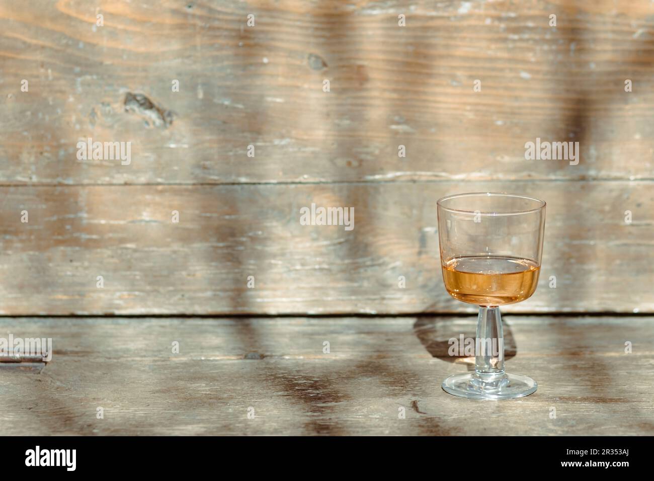 Liquor in a transparent drinking glass isolated on a textured wooden ...