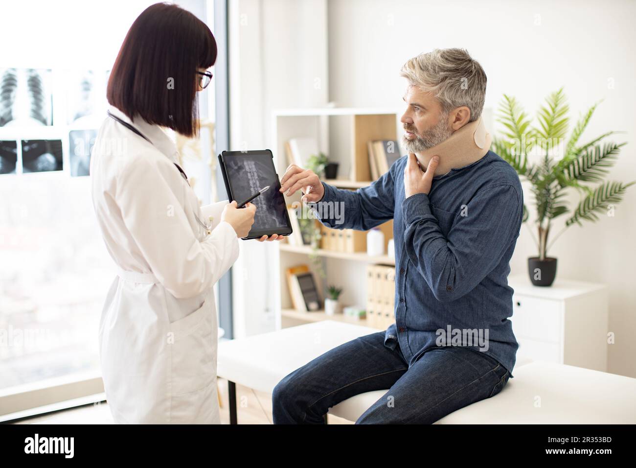Caucasian lady holding tablet with CT scan image on screen while ...