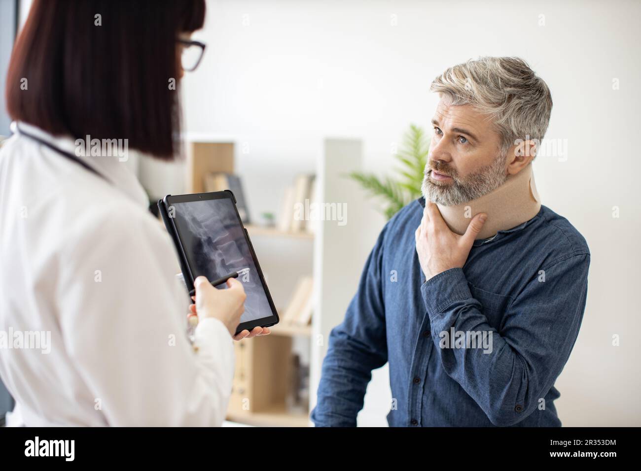Caucasian lady holding tablet with CT scan image on screen while ...