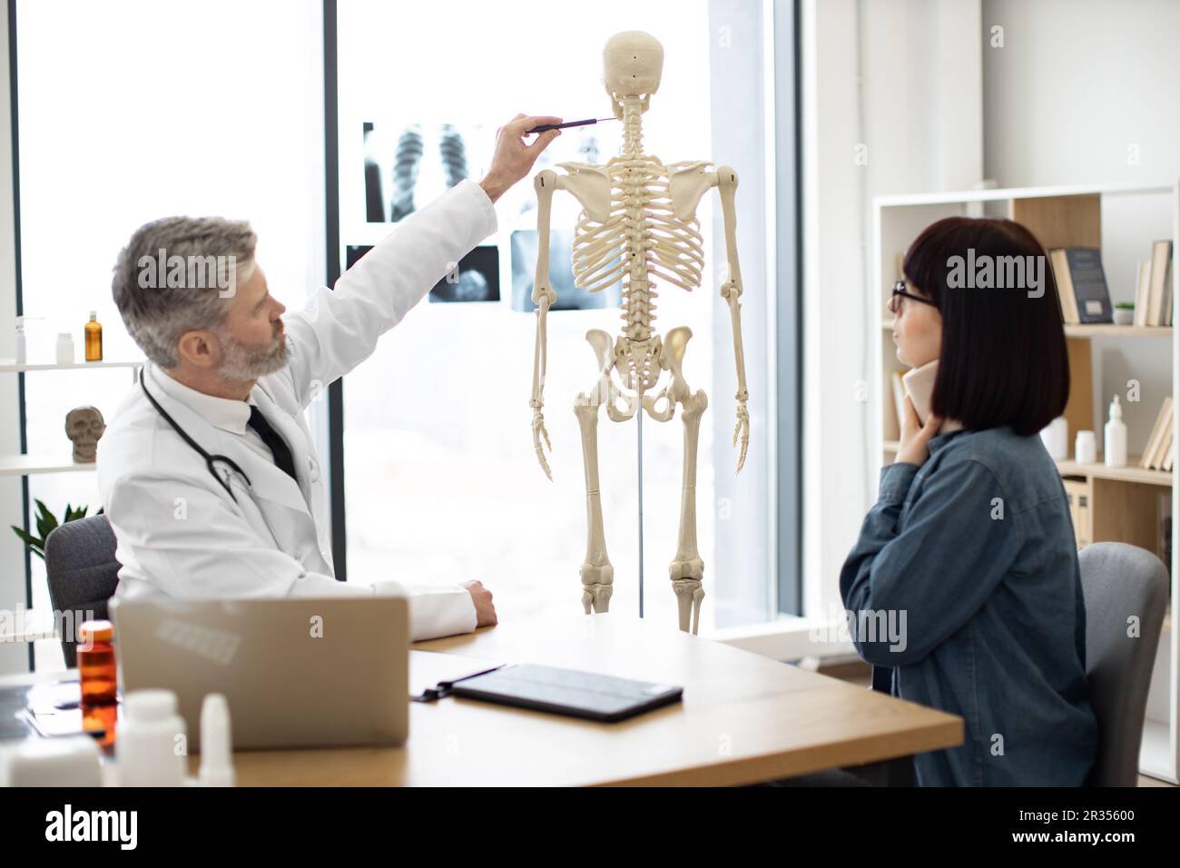 Gray-haired therapist with stethoscope marking spinal vertebrae on ...