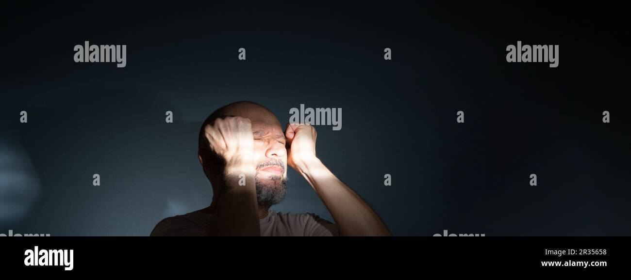 Man in his 50s, emotionally shaken showing stress or pain gesture ...